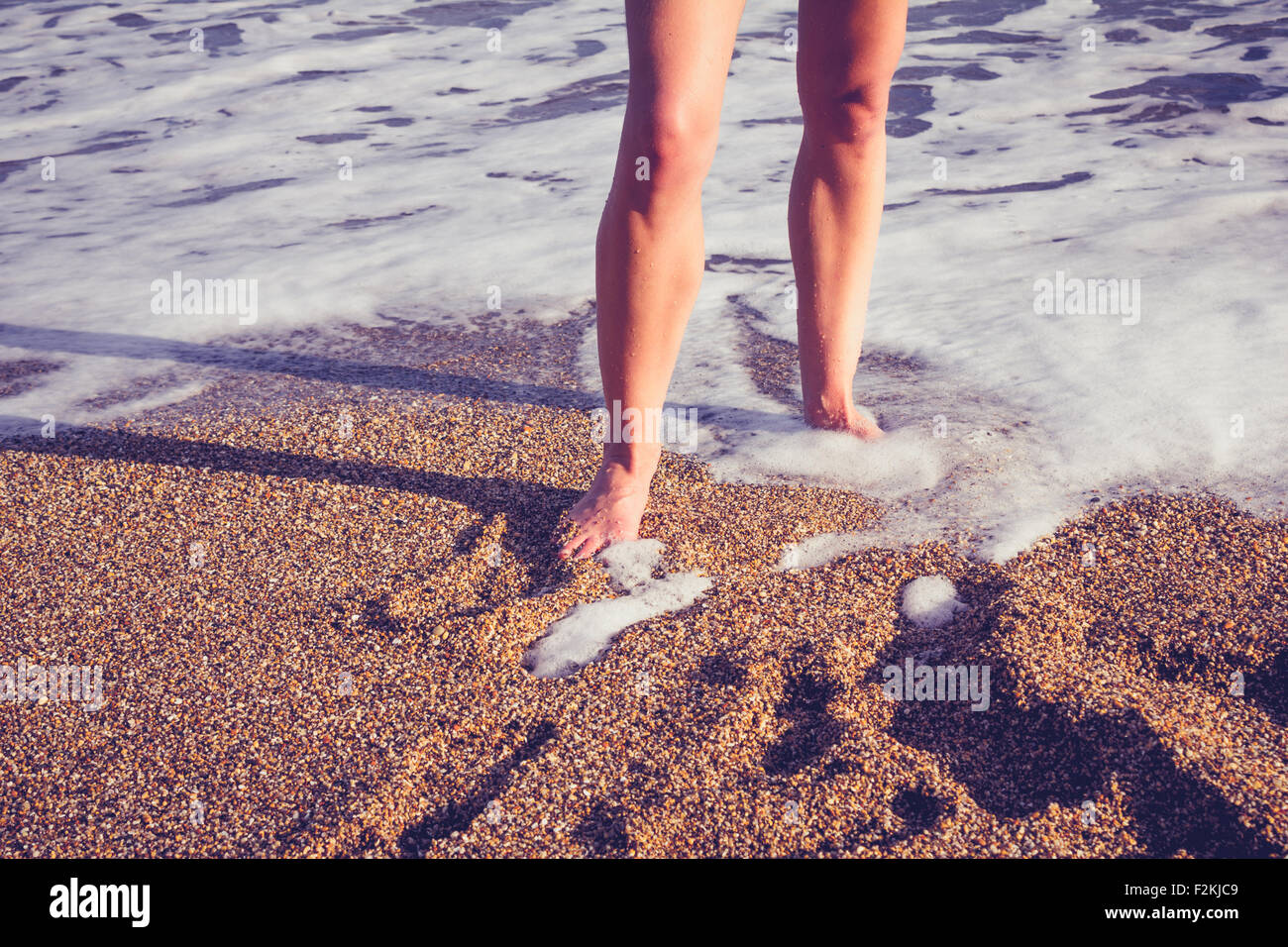 Young woman's leg in the surf on the beach Stock Photo - Alamy