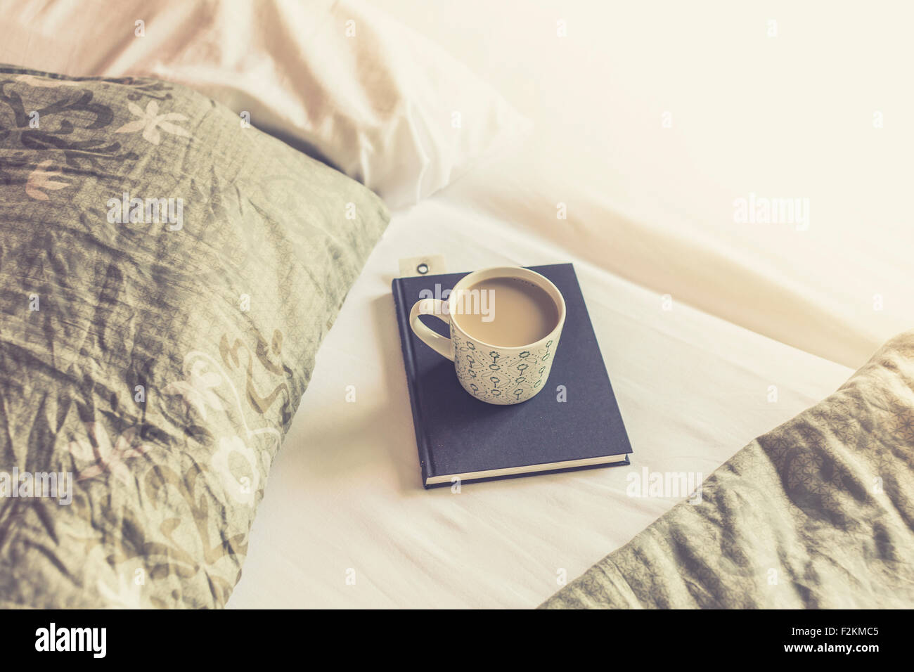 Book and cup of white coffee on a bed Stock Photo - Alamy