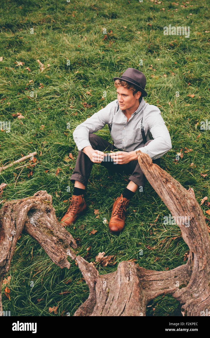 Young man wearing hat sitting on a meadow Stock Photo - Alamy