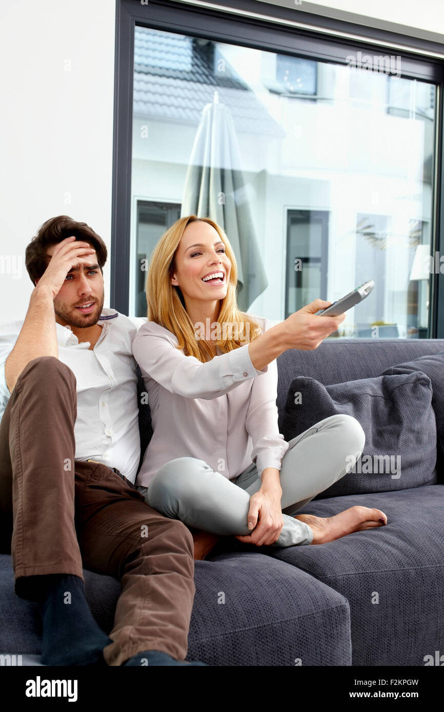 Couple sitting together on couch watching TV show Stock Photo - Alamy