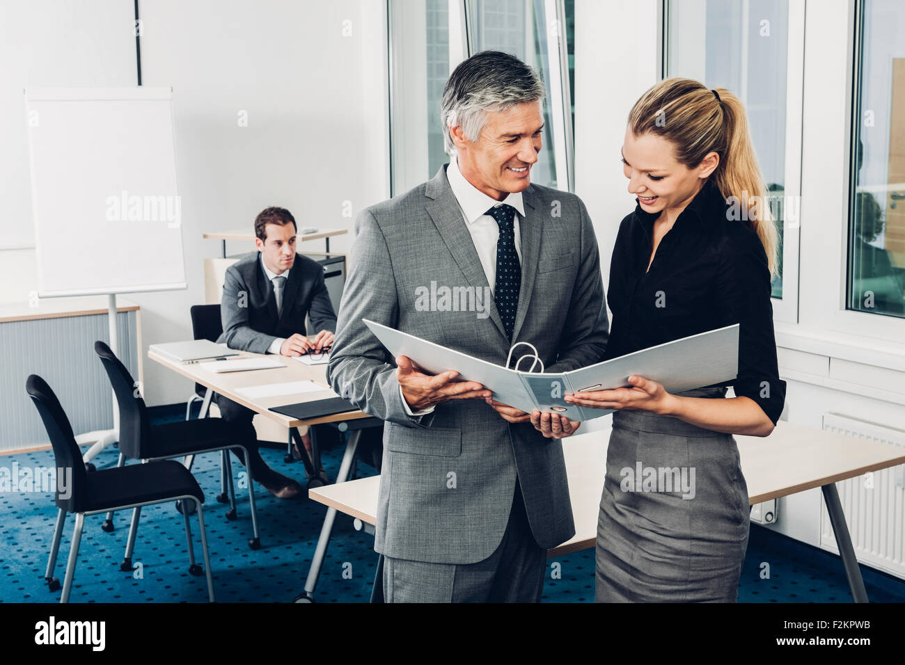 Business people reading report, standing in front of team Stock Photo ...