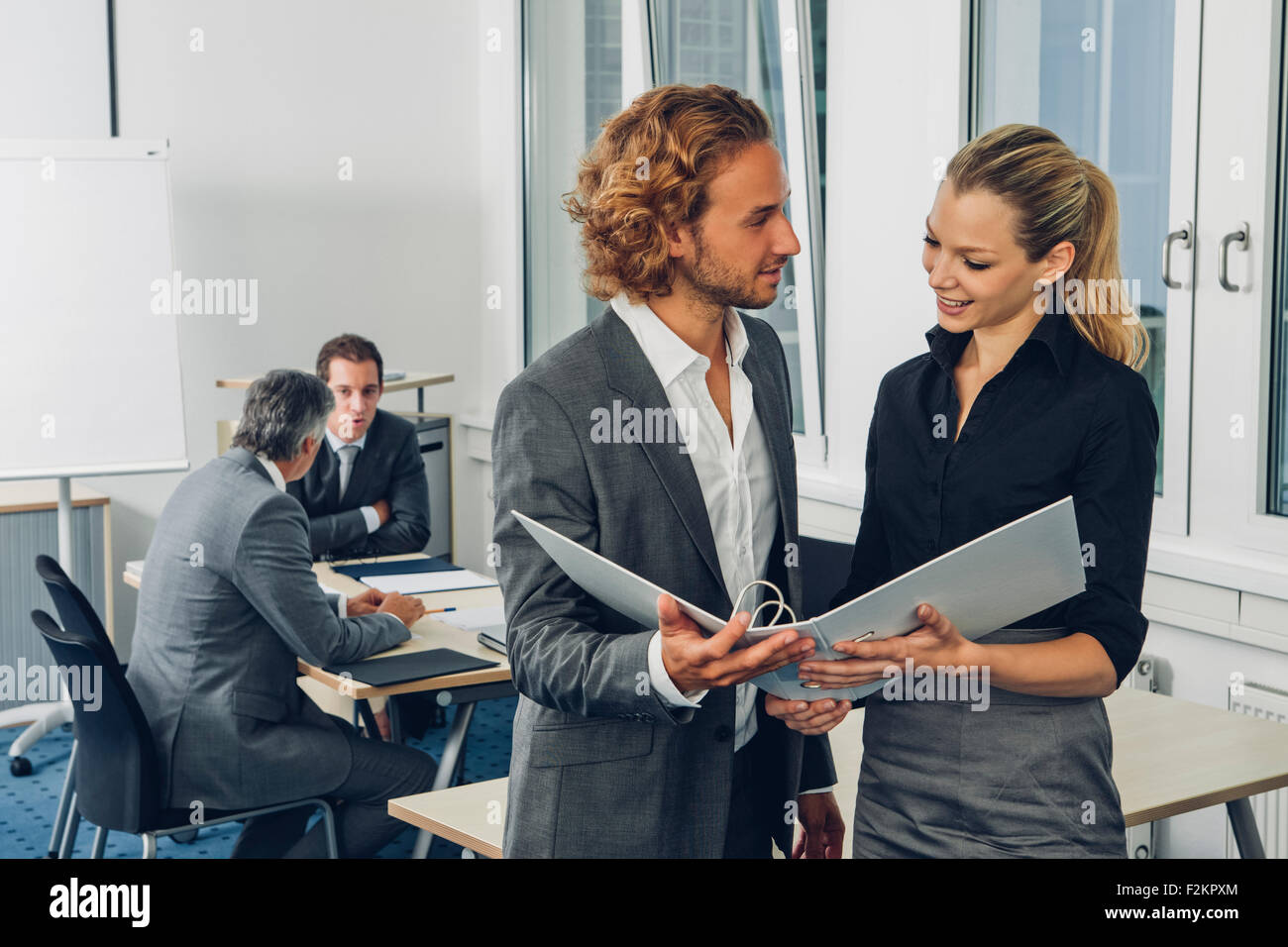 Business people reading report, standing in front of team Stock Photo ...