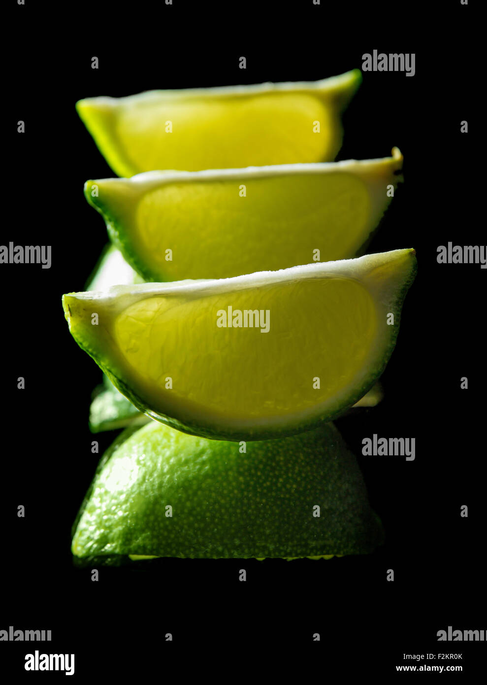 backlit quarters of lime fruit on black mirror Stock Photo - Alamy