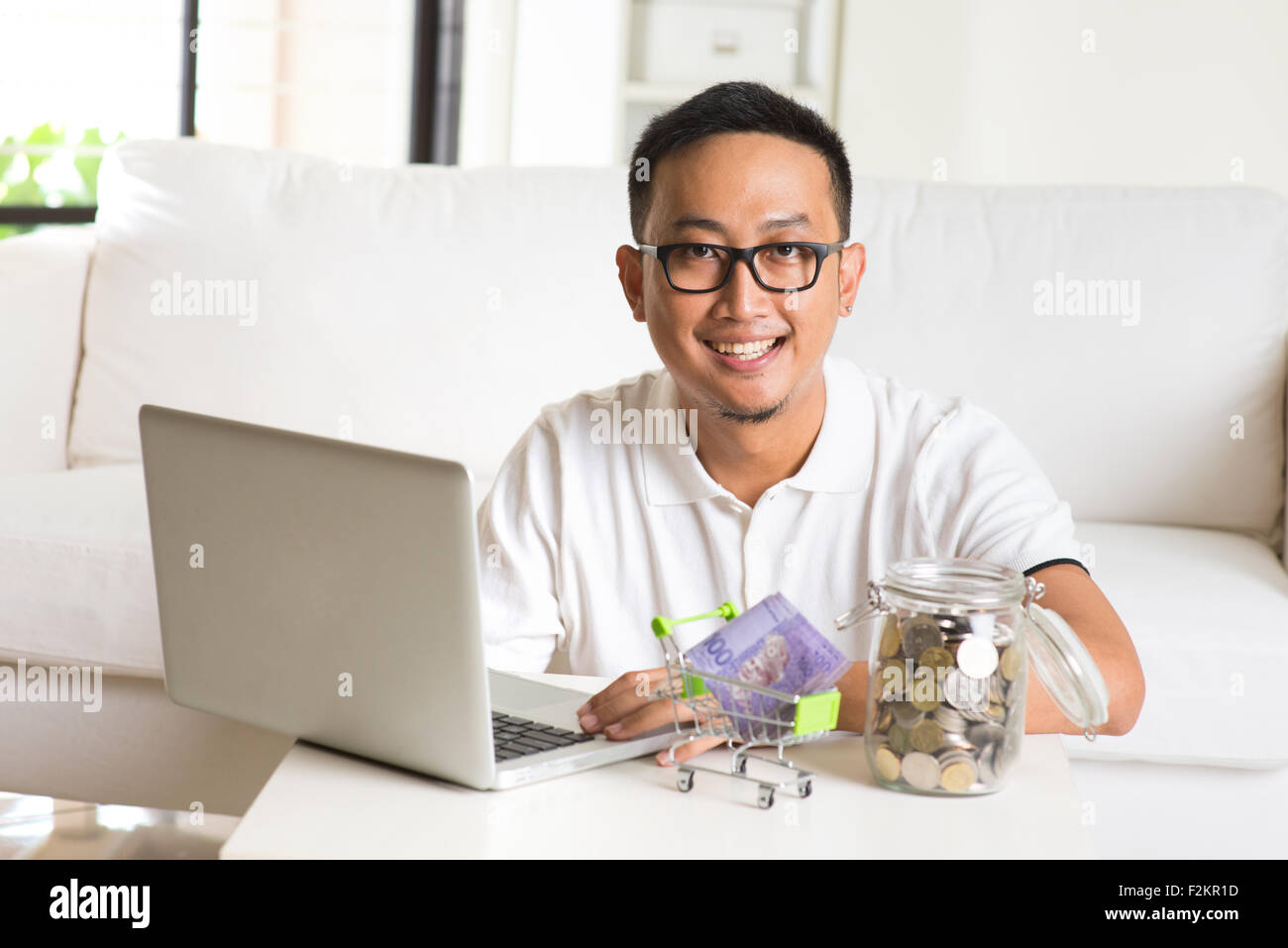 asian guy using internet computer and counting coins at home. Asian man ...