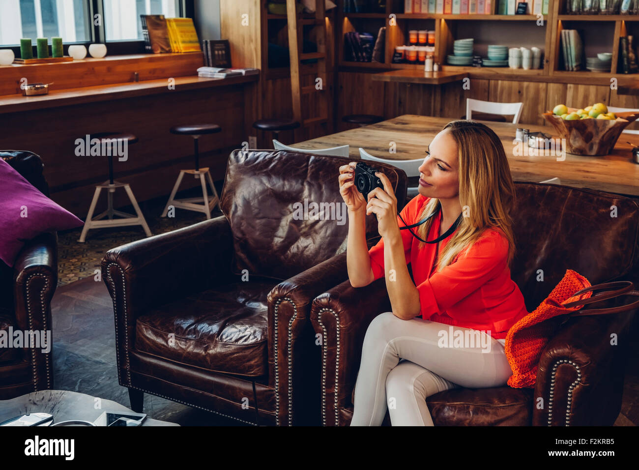 Blond woman sitting in a coffee shop taking pictures with her digital ...