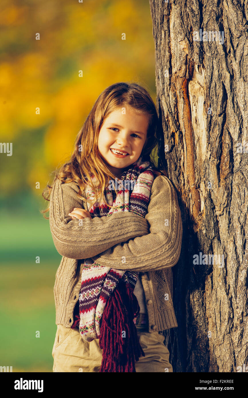 Portrait of smiling girl leaning on tree trunk Stock Photo - Alamy