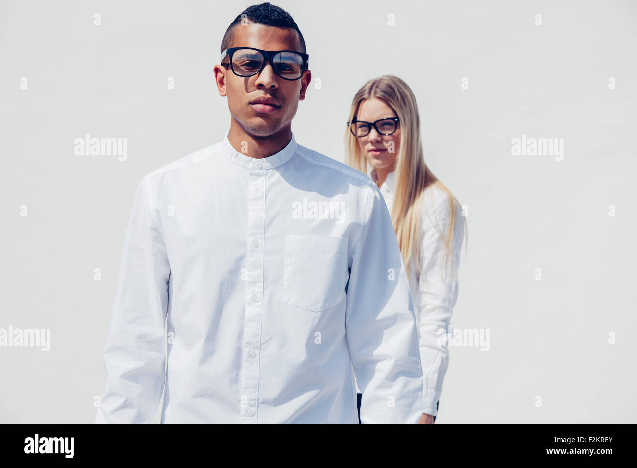 Portrait of stylish young couple wearing matching clothes in front of ...
