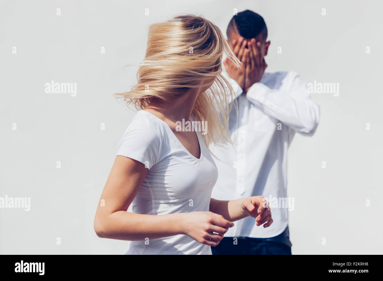 Young blond woman turning head back looking at young man standing in ...