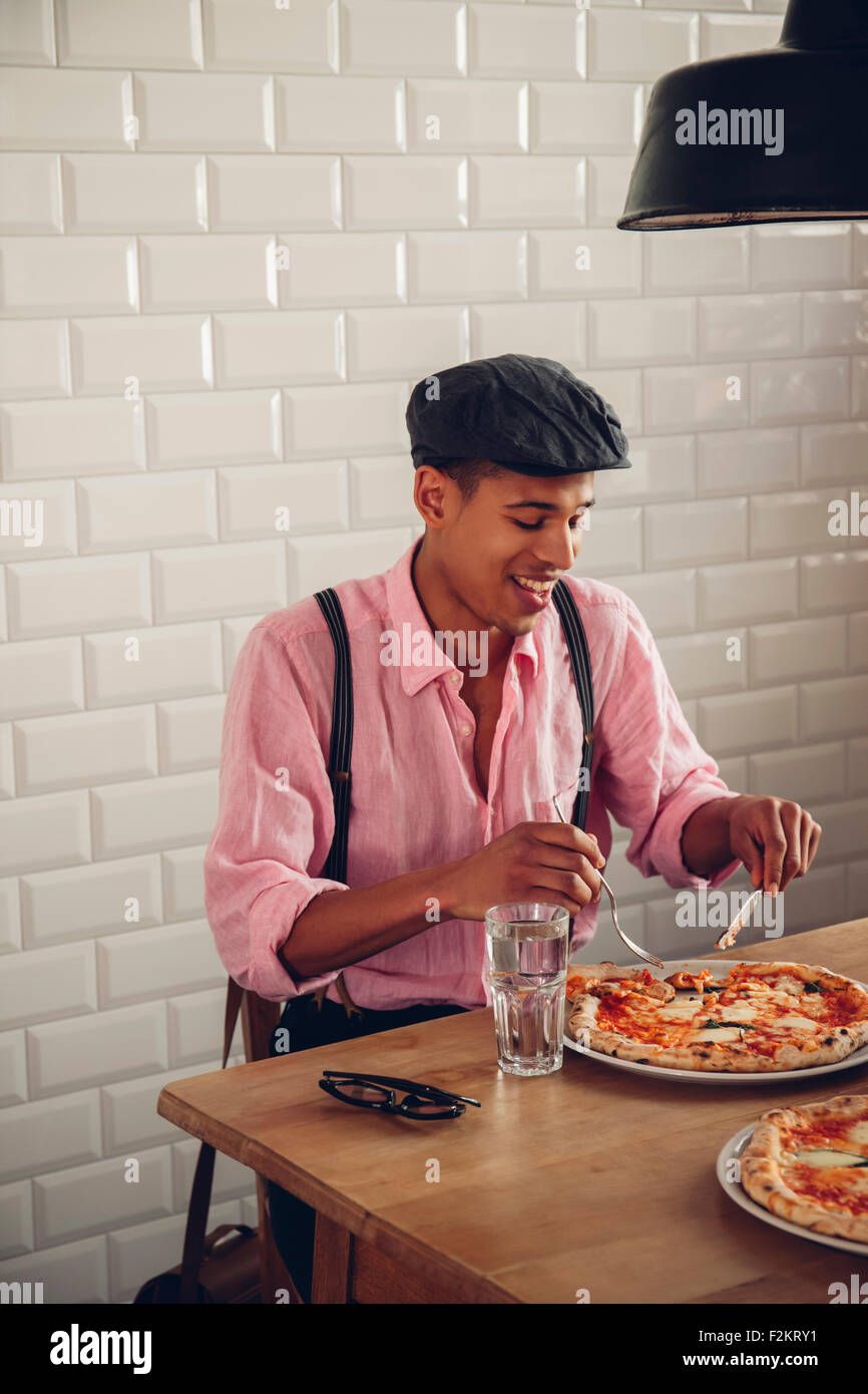 Young man eating pizza in restaurant Stock Photo - Alamy