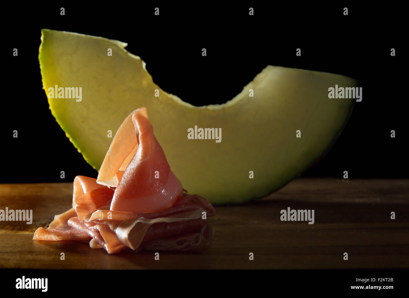Ham and Melon still life on black background Stock Photo - Alamy
