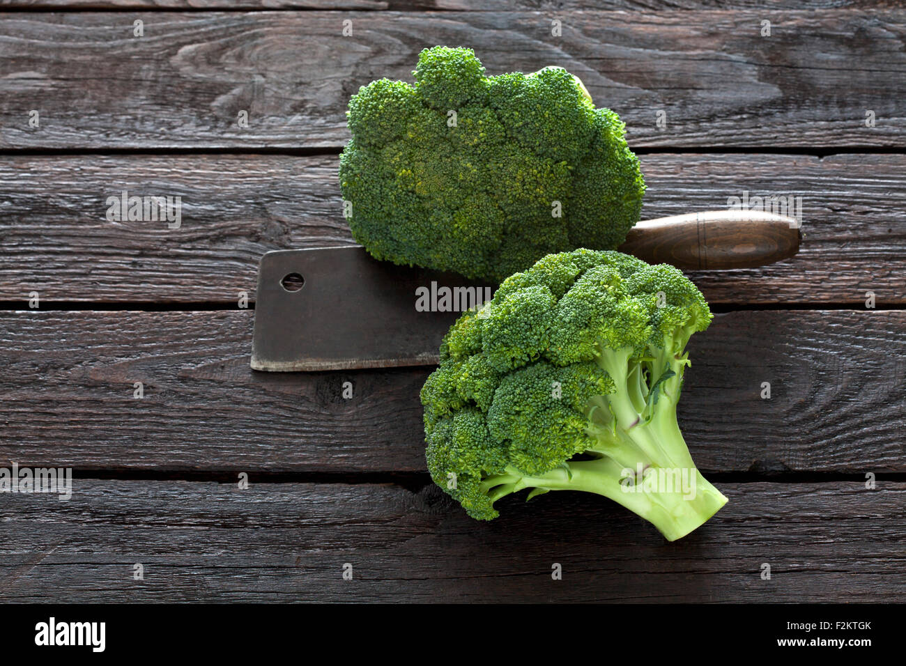 Two broccoli florets and kitchen cleaver on dark wood Stock Photo - Alamy