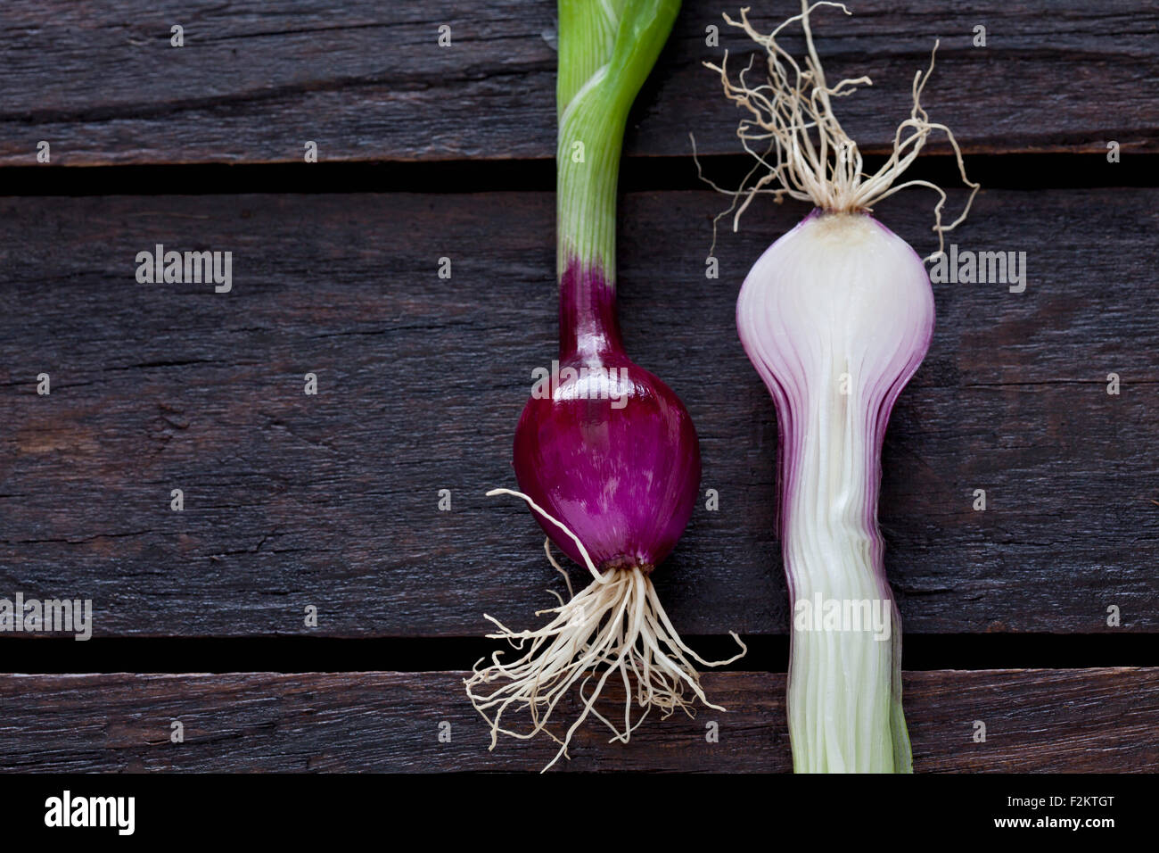 Whole and sliced red spring onions on dark wood Stock Photo - Alamy
