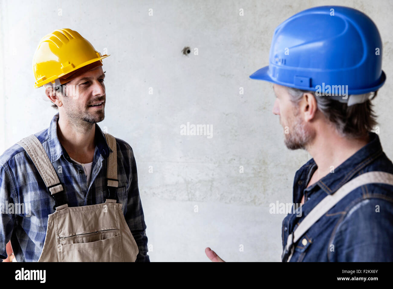 Two construction workers on construction site talking Stock Photo - Alamy