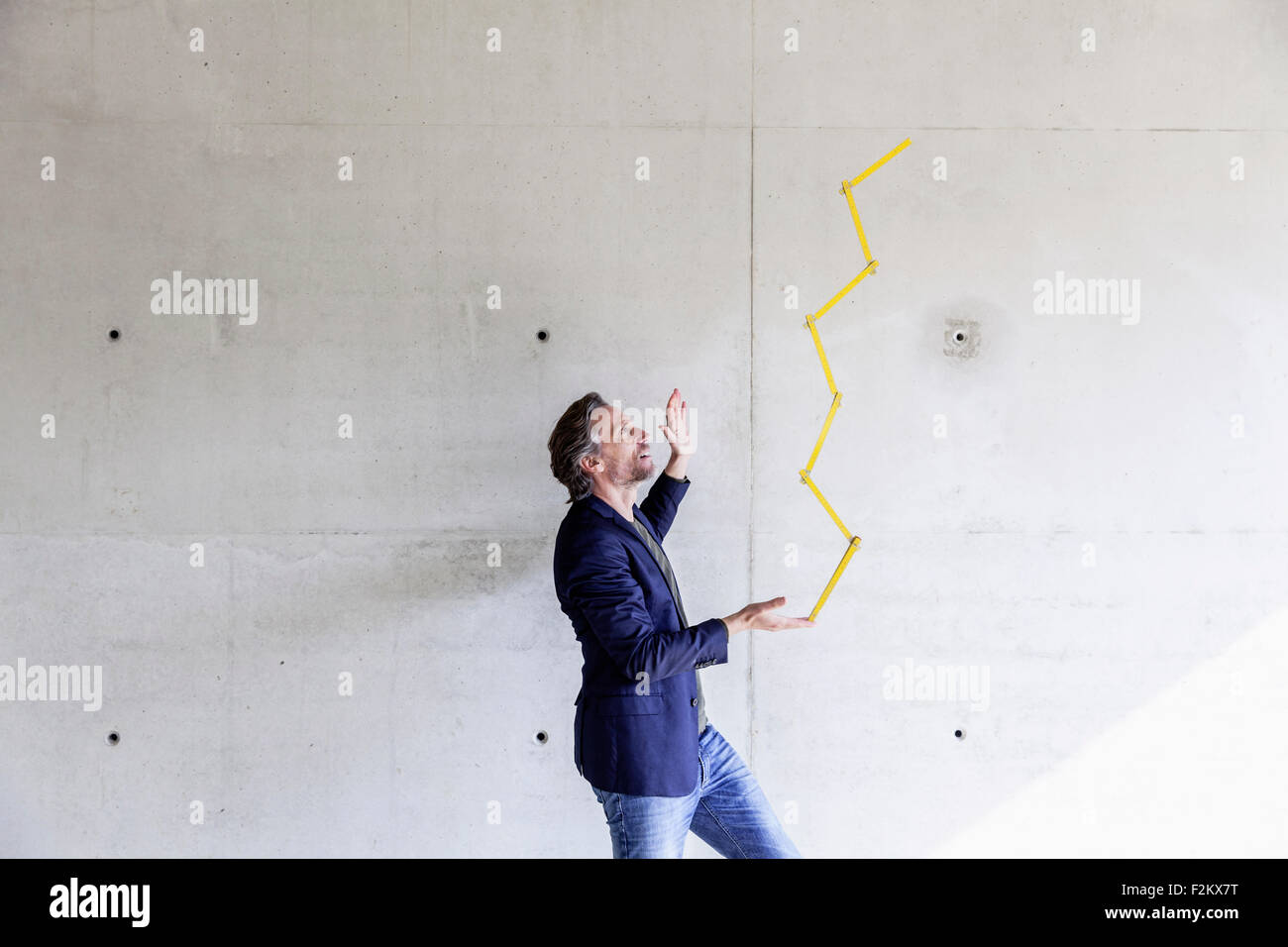 Man balancing poket rule in front of concrete wall Stock Photo - Alamy