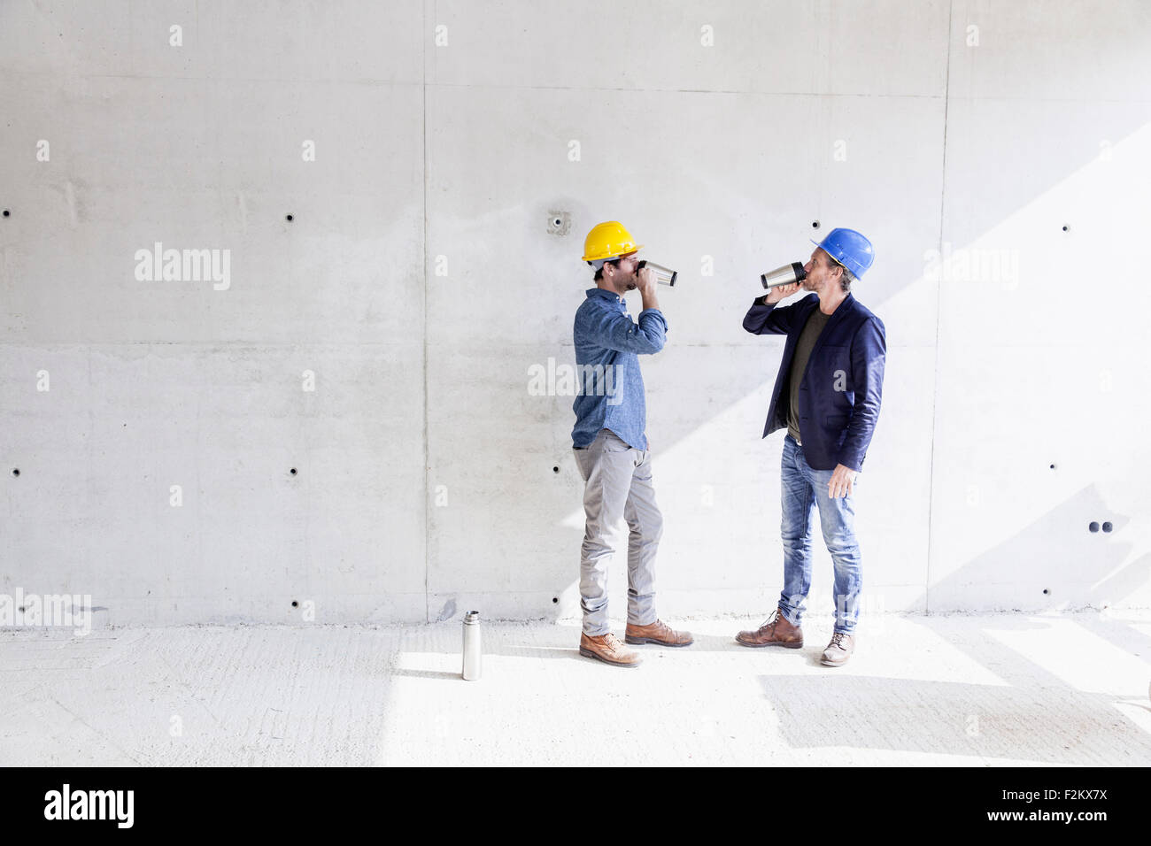 Two men on construction site drinking from mugs Stock Photo - Alamy