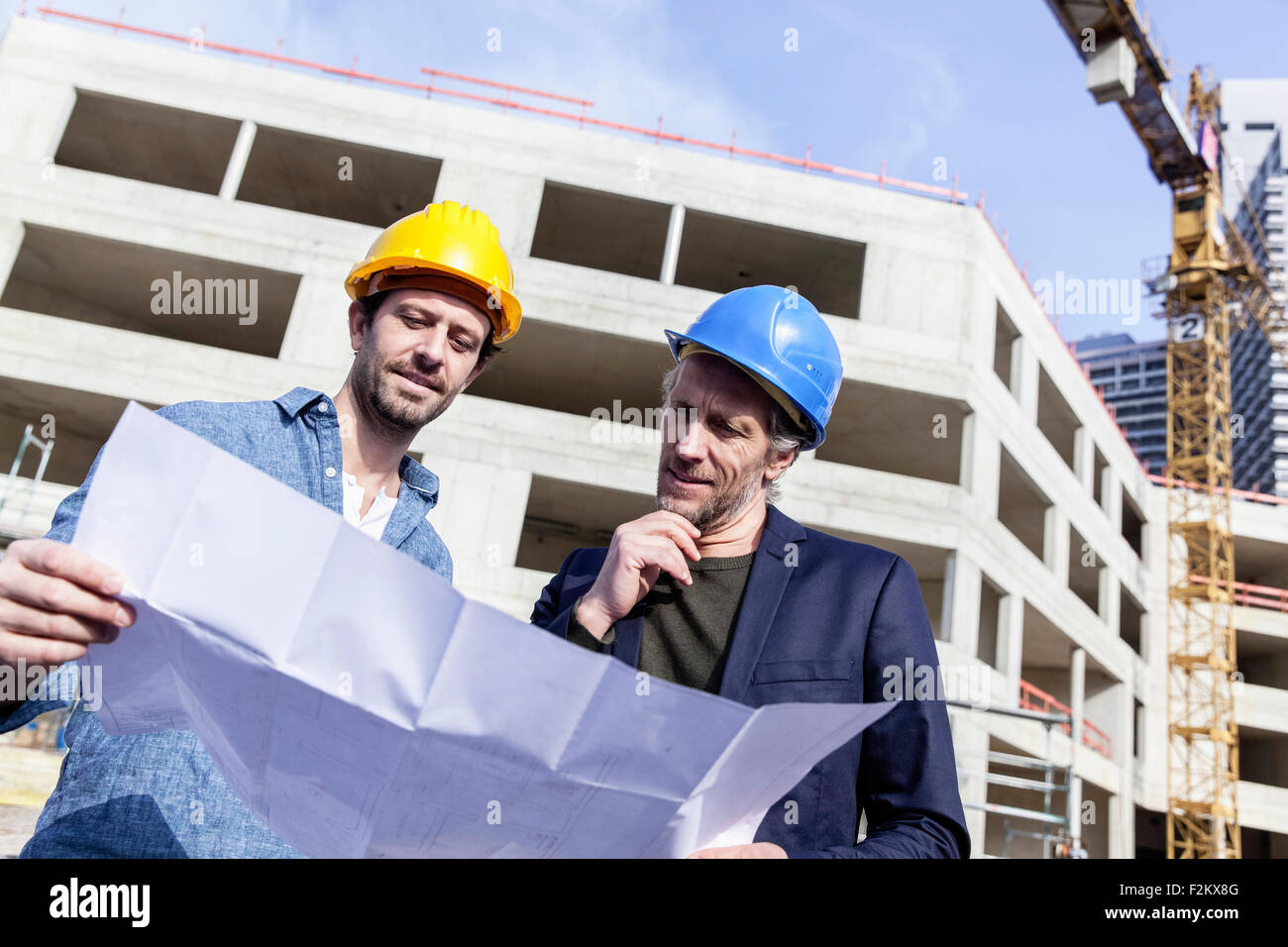 Two men on construction site looking at construction plan Stock Photo ...