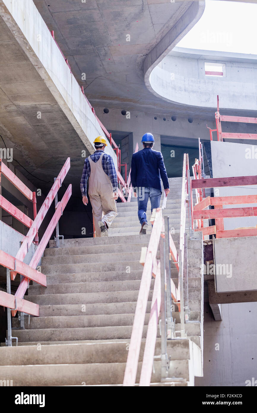 Construction worker and architect on construction site walking upstairs ...