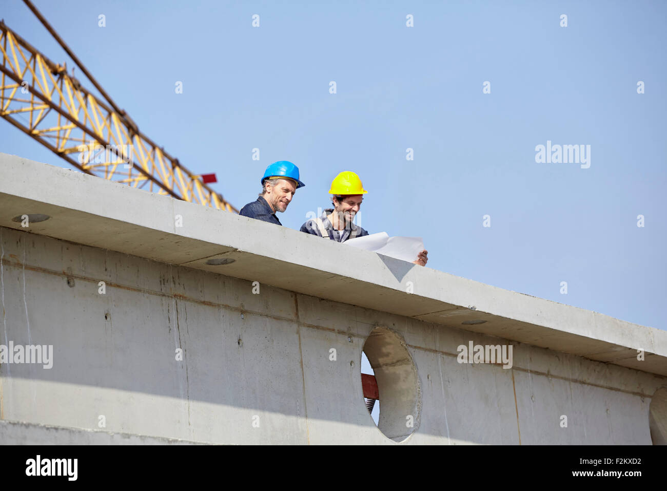 Two men on construction site looking at construction plan Stock Photo ...