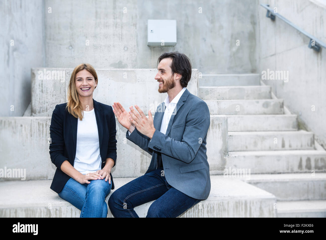 Two business people sitting on concrete steps Stock Photo - Alamy