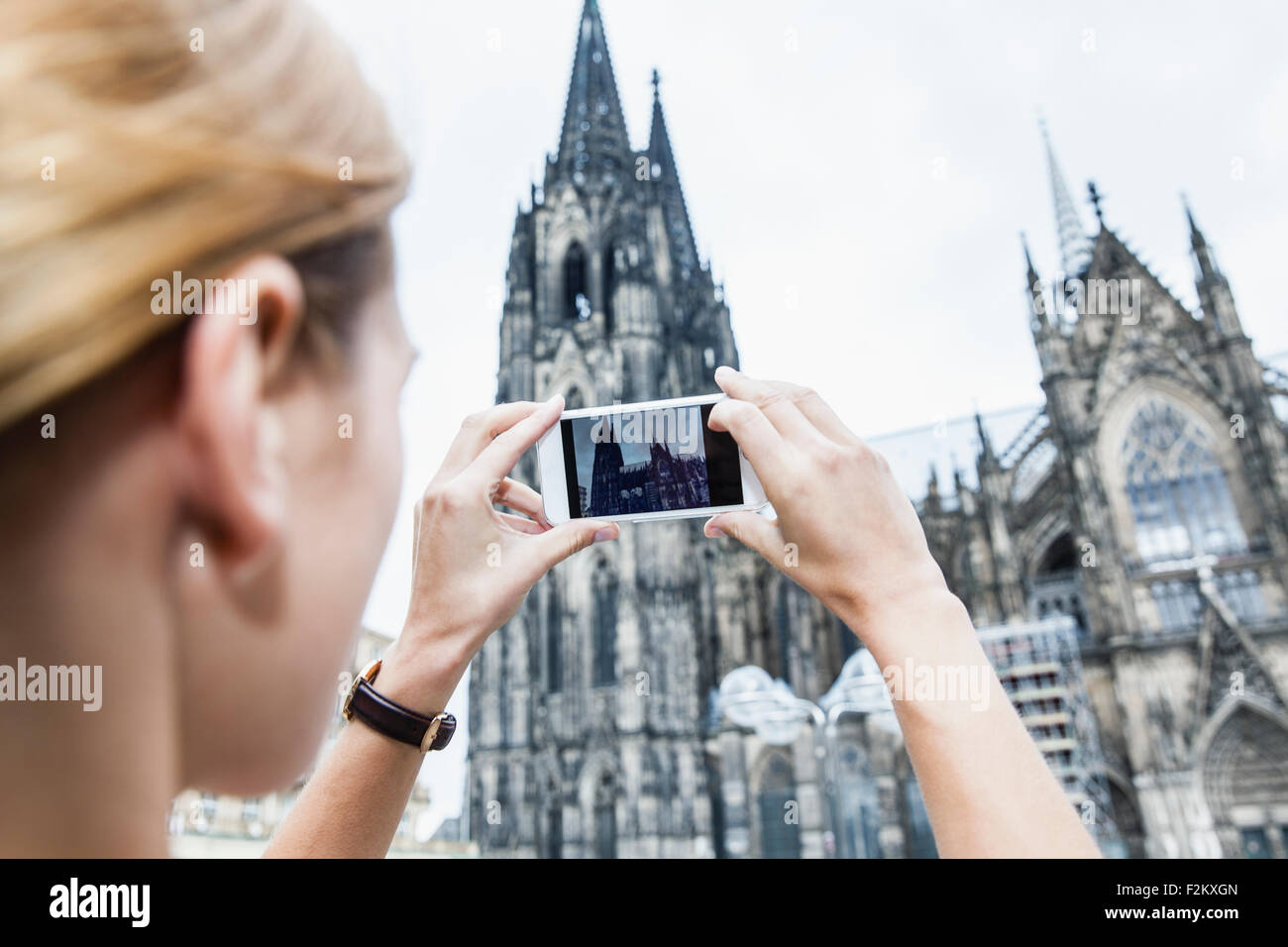 Germany, Cologne, young woman taking a picture of Cologne Cathedral ...