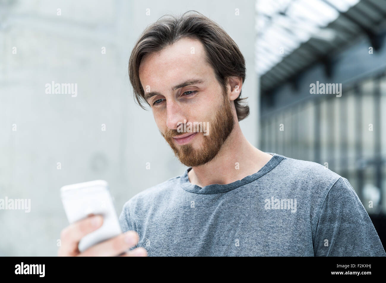 Portrait of young man looking at his smartphone Stock Photo - Alamy