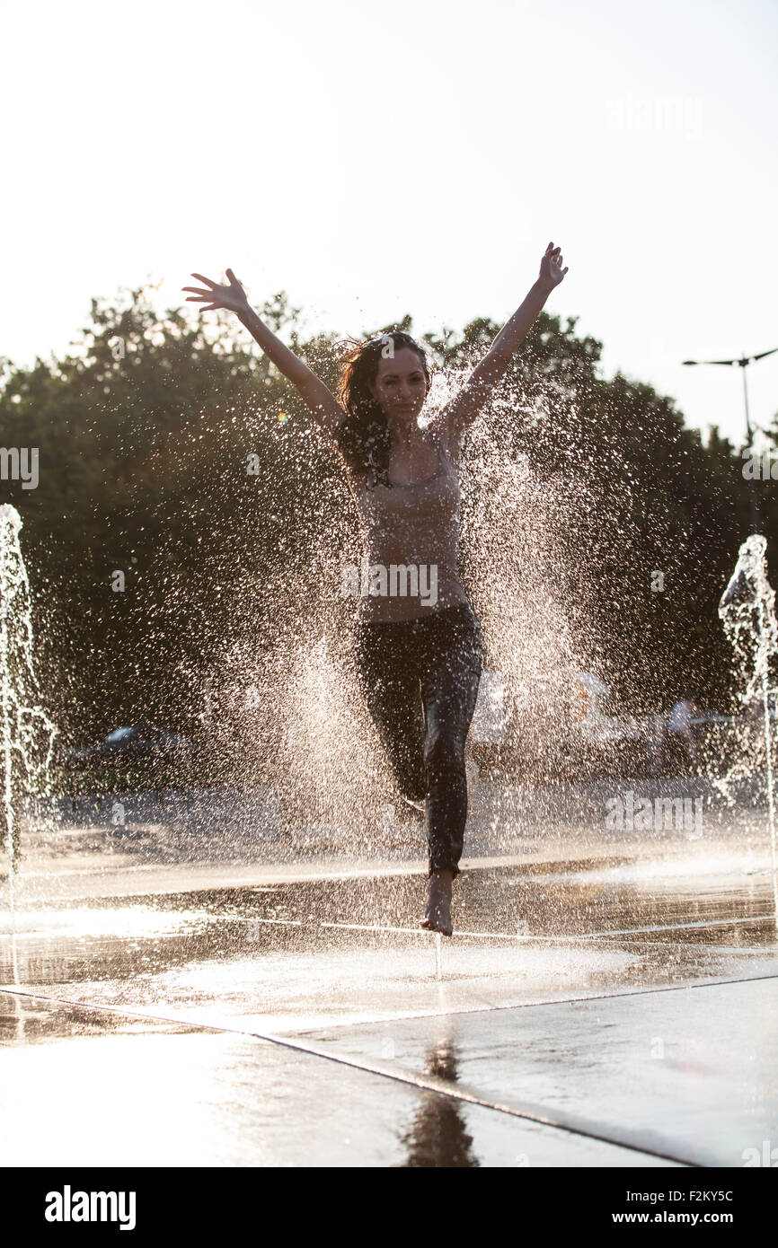 Woman running through fountain splashing water drops Stock Photo - Alamy