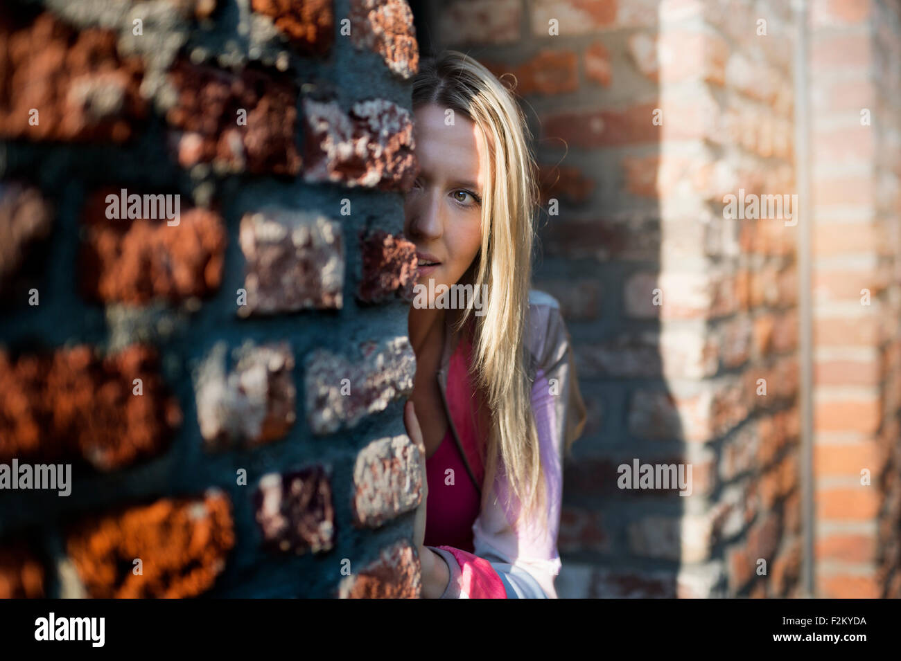 Blond woman hiding at house entrance Stock Photo - Alamy