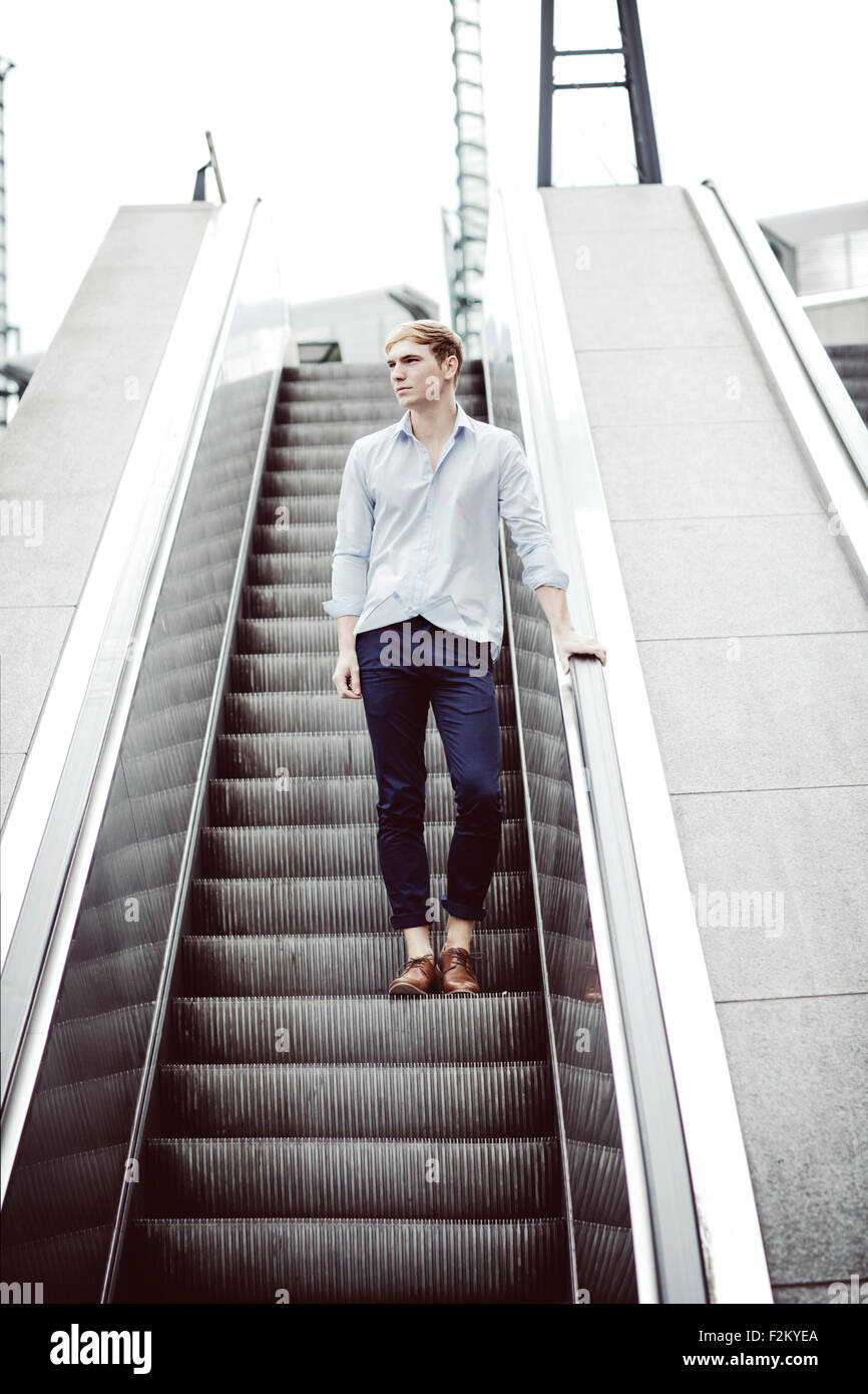 Young man standing on escalator Stock Photo - Alamy