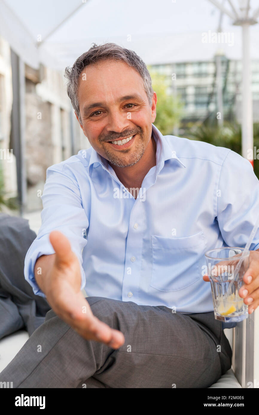 Portrait of smiling man reaching out his hand Stock Photo - Alamy