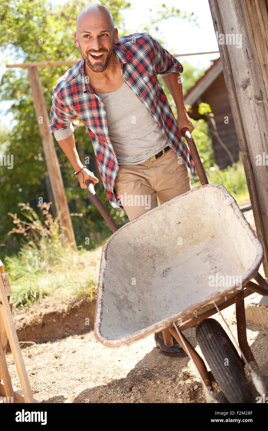 Portrait of smiling man with wheelbarrow Stock Photo - Alamy