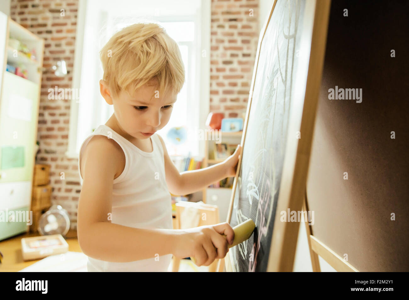 Little boy drawing on chalk board in children's room Stock Photo - Alamy