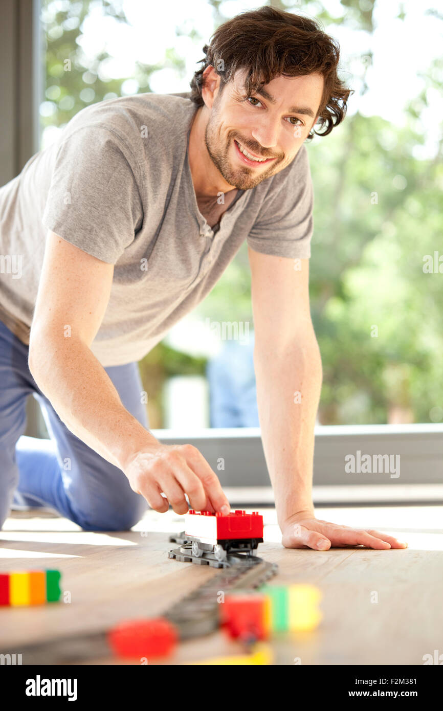 Smiling man playing with toy train Stock Photo - Alamy