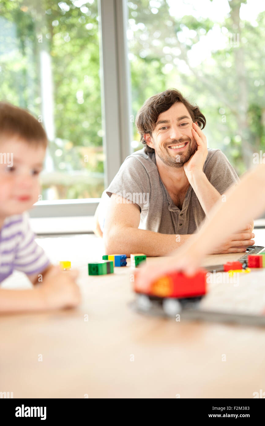 Father lying on floor watching children playing with toy train Stock ...