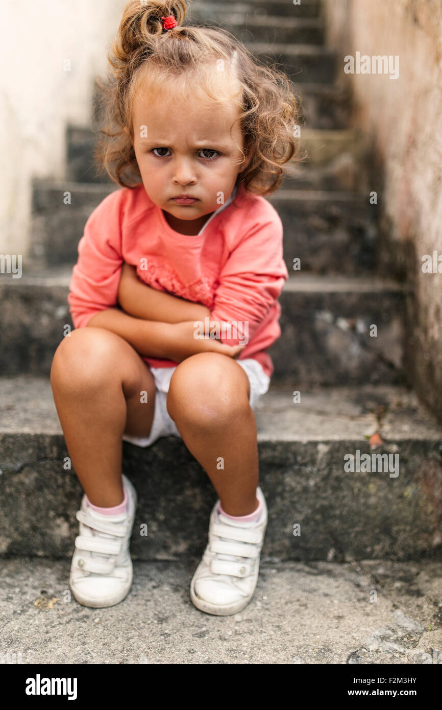 Portrait of little girl sitting on steps pouting mouth Stock Photo - Alamy