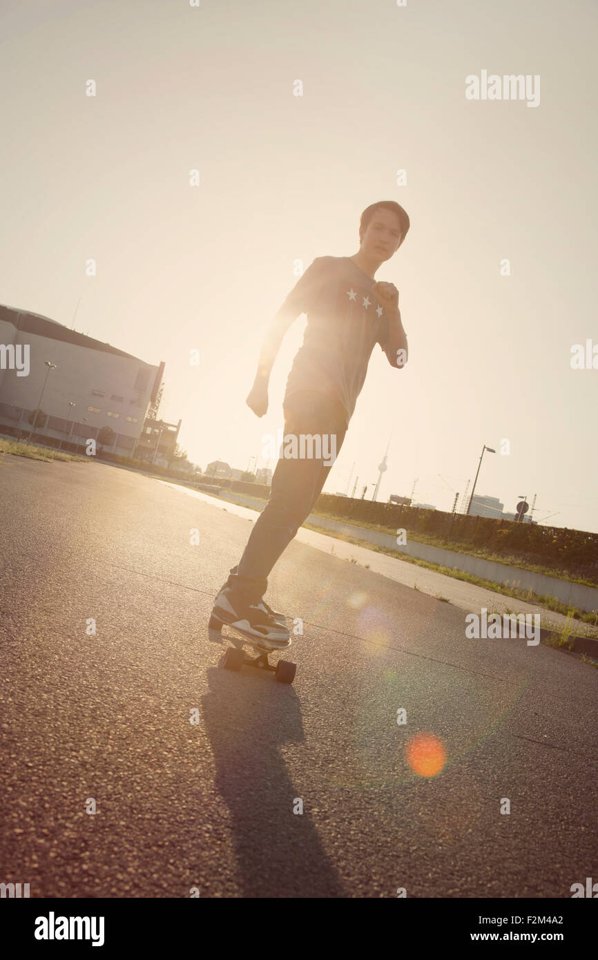 Teenage boy on a longboard at backlight Stock Photo - Alamy