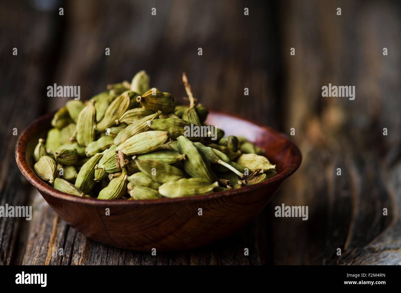 Wooden bowl with cardamom capsules Stock Photo - Alamy