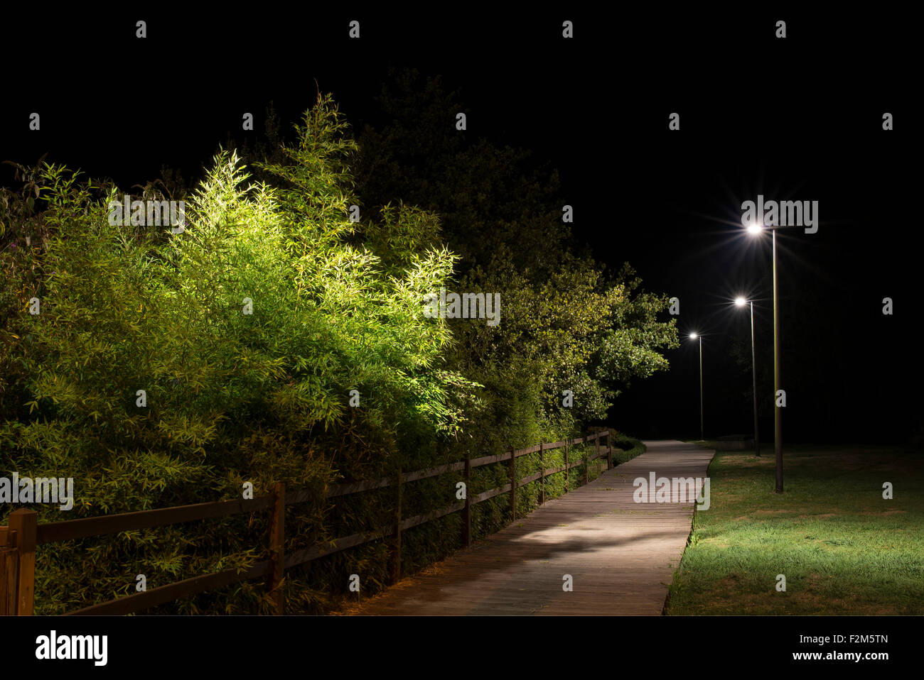 Spain, Naron, walkway in a park lighted by street lamps at night Stock ...