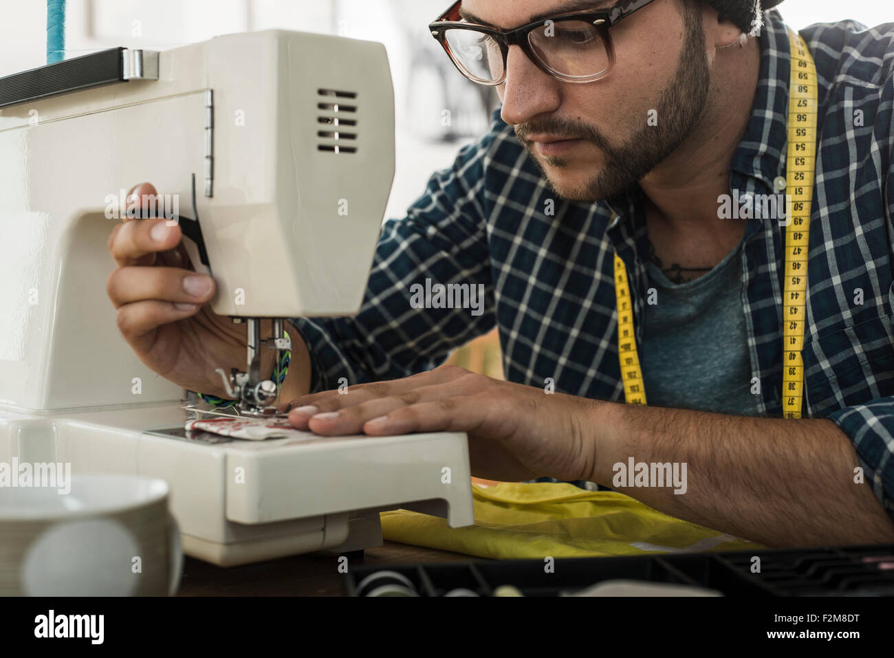 Young man at home using sewing machine Stock Photo - Alamy