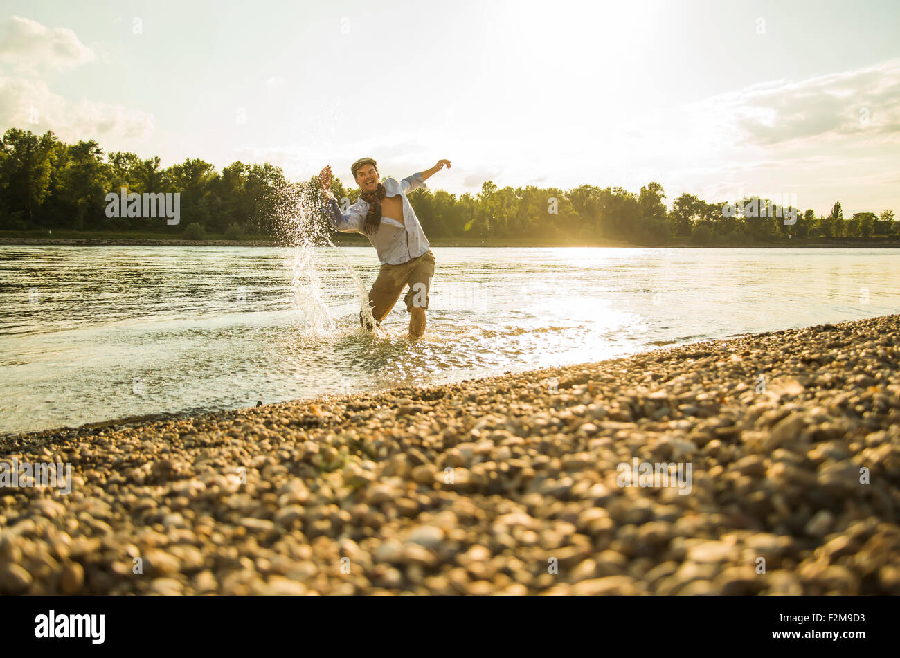 Man standing at riverside splashing with water Stock Photo - Alamy