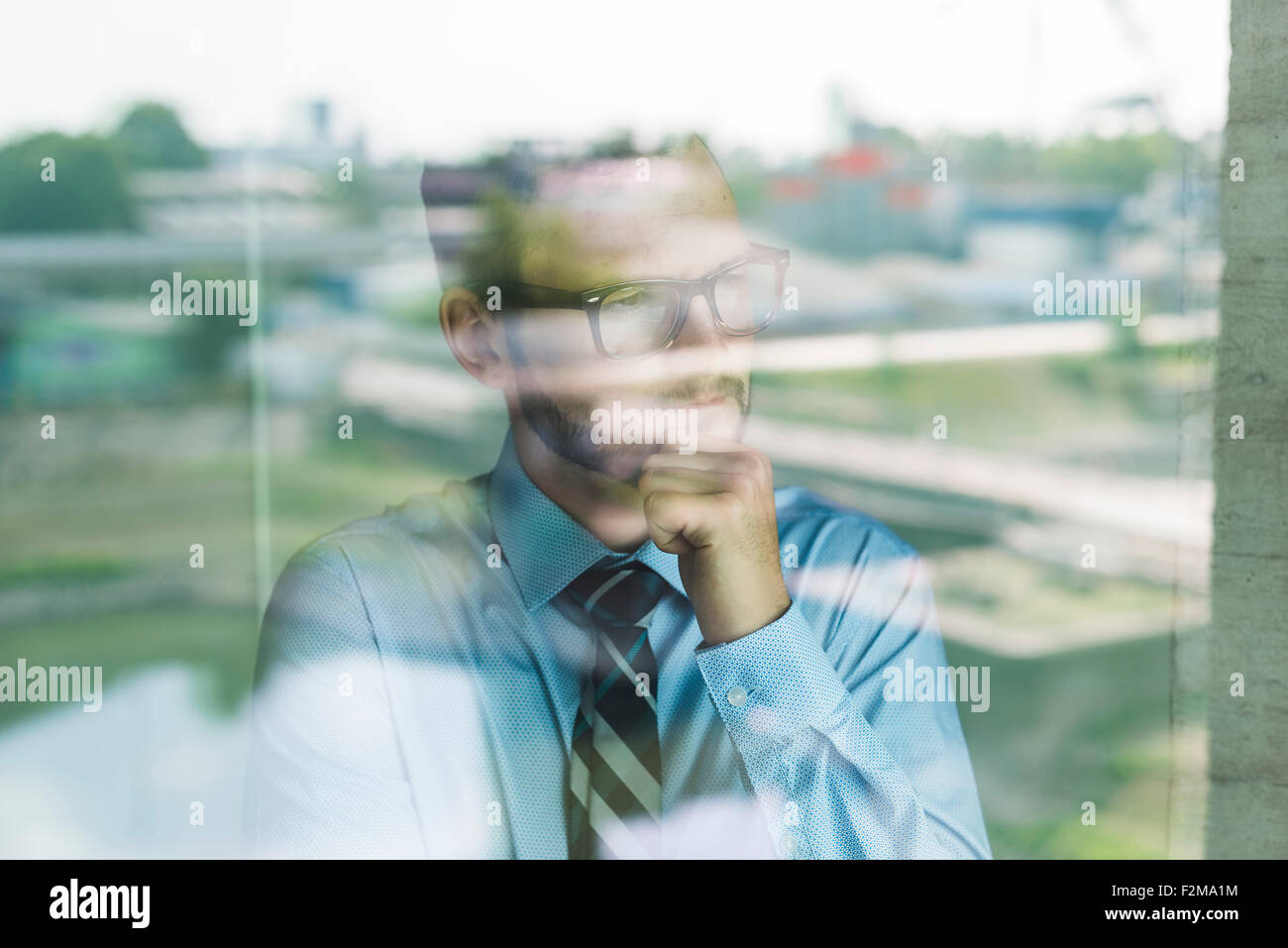 Young businessman looking out of window Stock Photo - Alamy