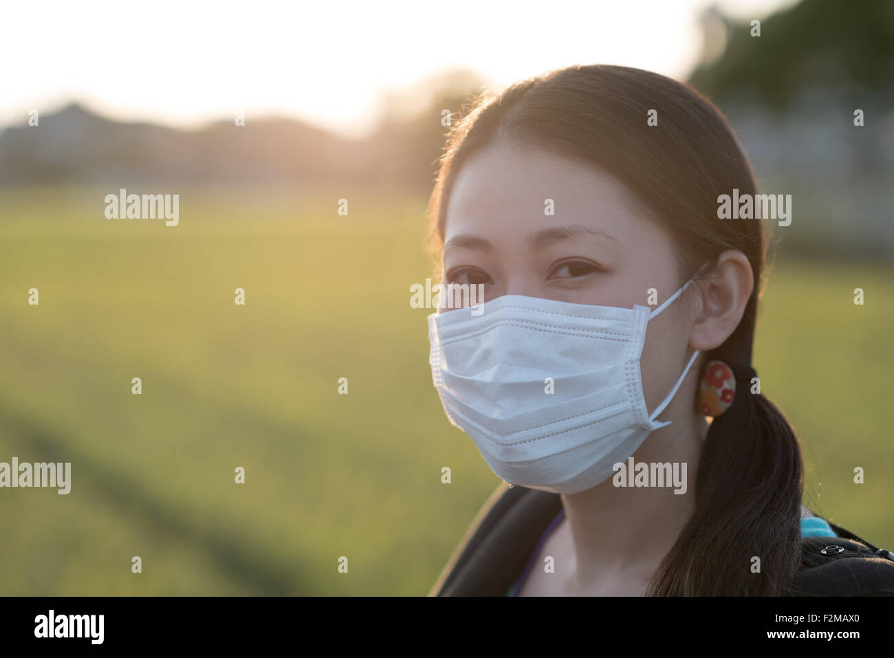 A young Japanese woman wearing a surgical mask outdoors in the ...
