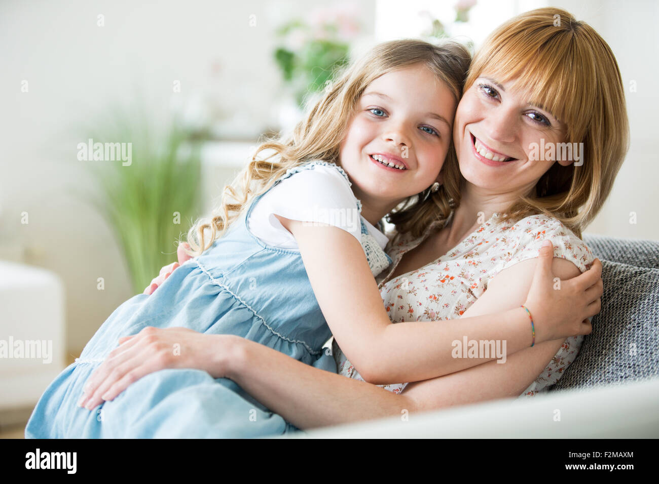 Mother and daughter sitting on couch, cuddling Stock Photo - Alamy