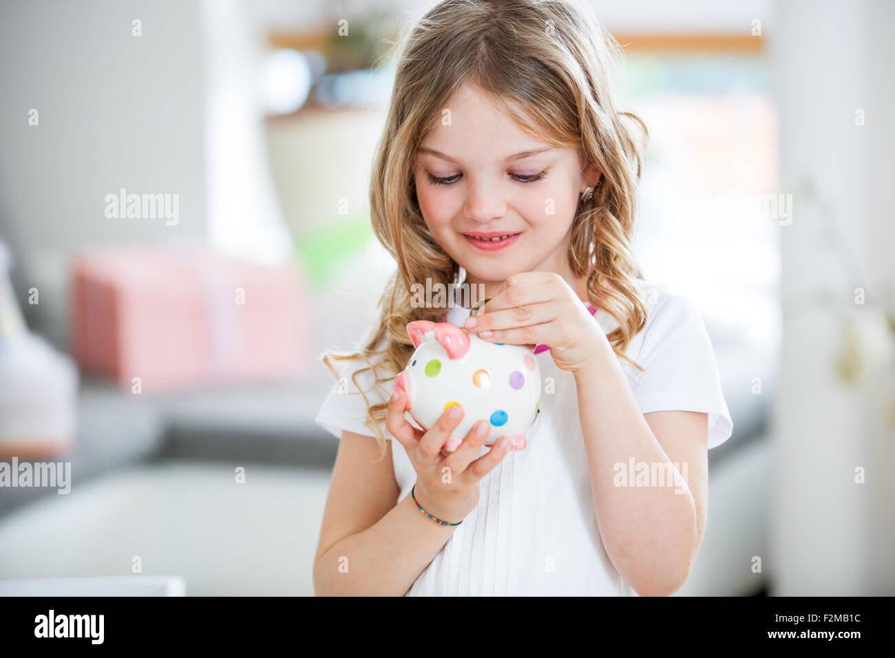 Girl throwing coin into piggy bank Stock Photo - Alamy