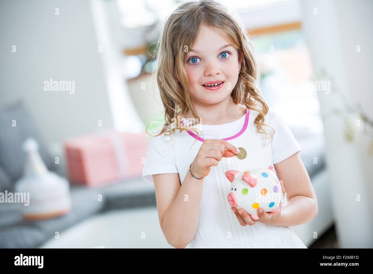 Girl throwing coin into piggy bank Stock Photo - Alamy