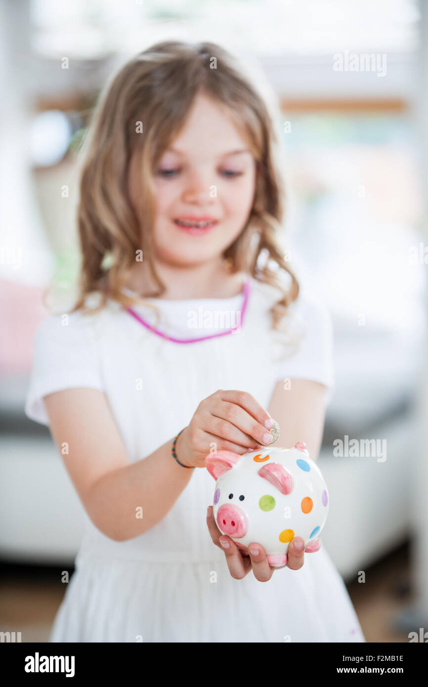 Girl throwing coin into piggy bank Stock Photo - Alamy