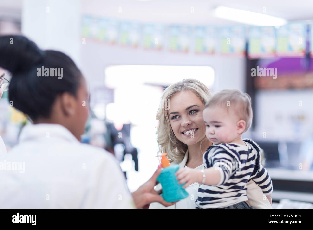 Pharmacist assisting client with baby in drugstore Stock Photo - Alamy