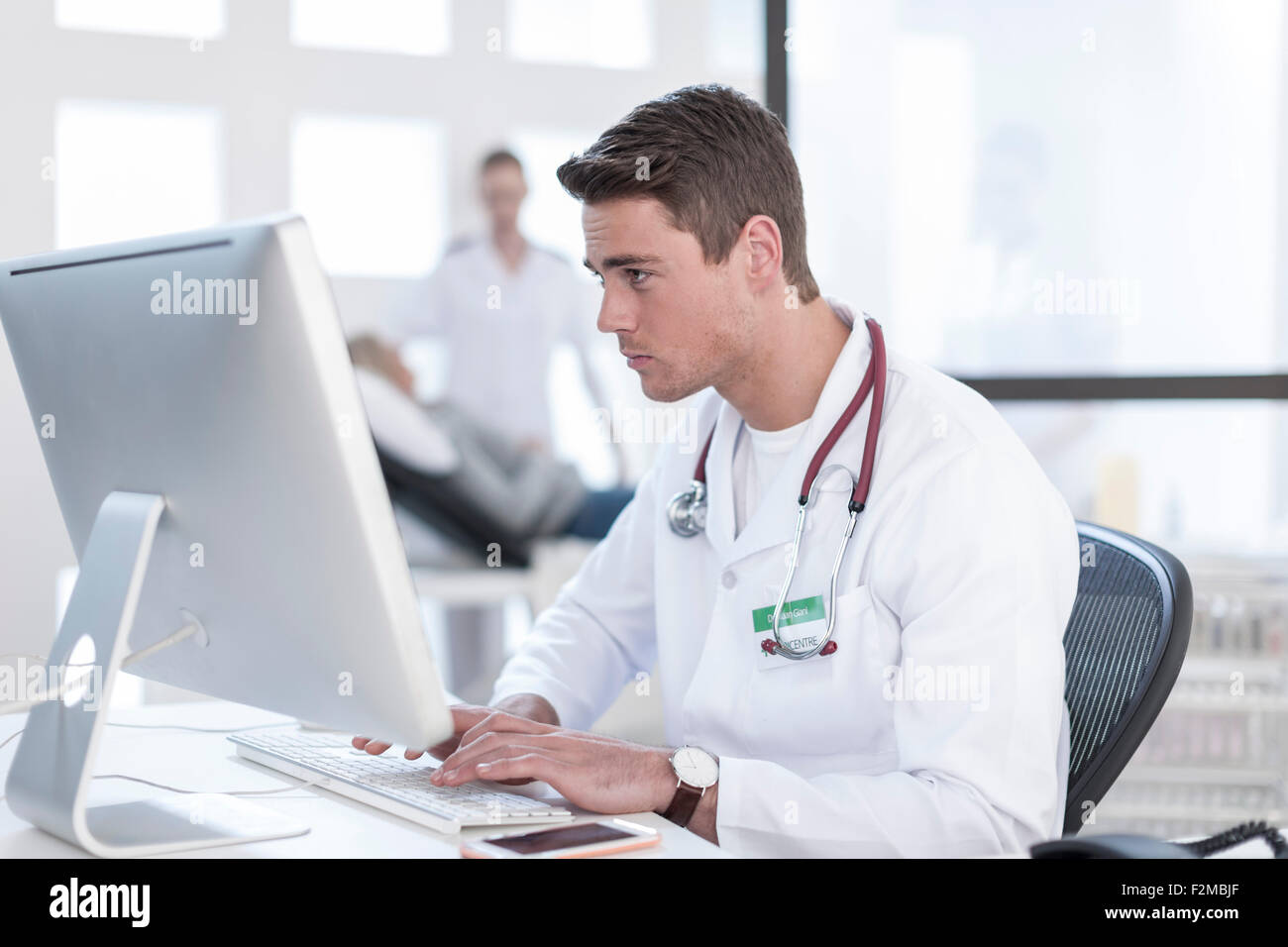 Doctor sitting at desk working on computer Stock Photo - Alamy