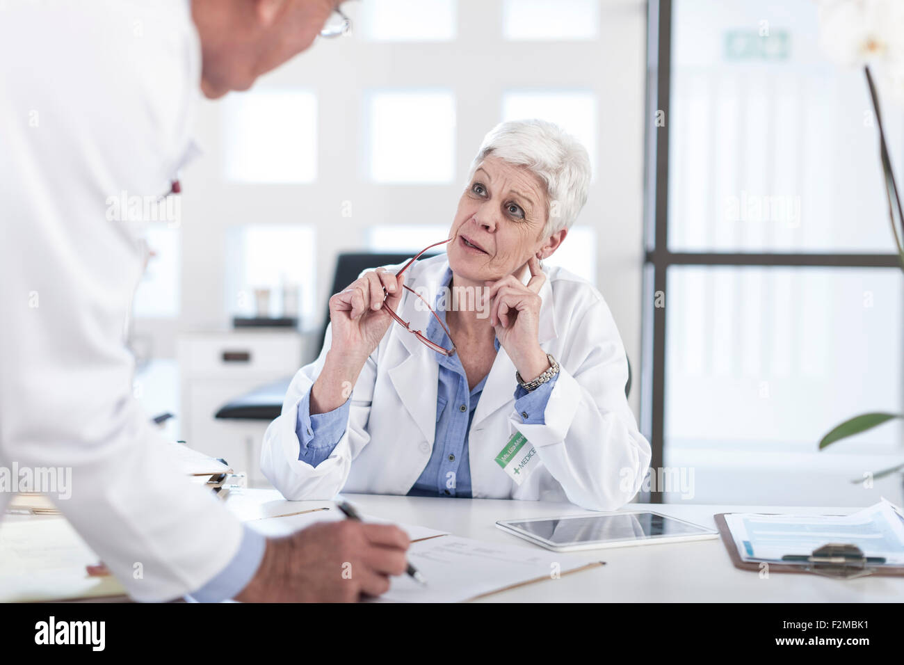 Two doctors talking at desk Stock Photo - Alamy