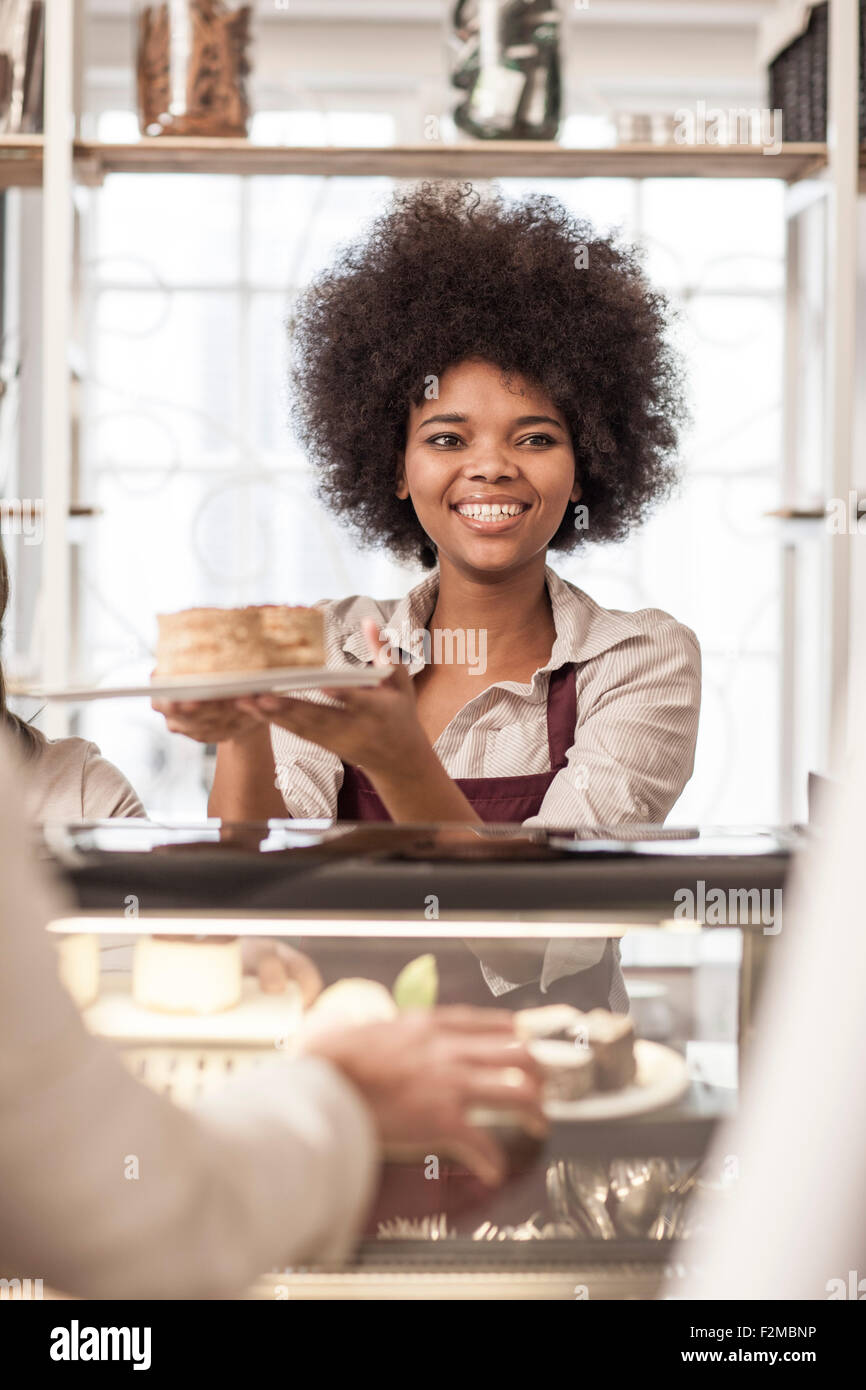 Young woman serving cake at cake counter in coffee shop Stock Photo - Alamy