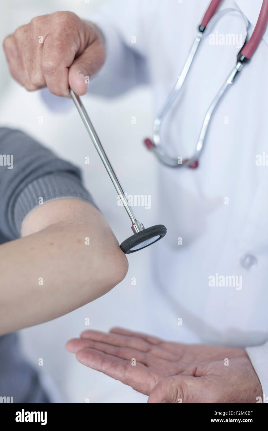 Doctor tapping patient with reflex hammer Stock Photo - Alamy